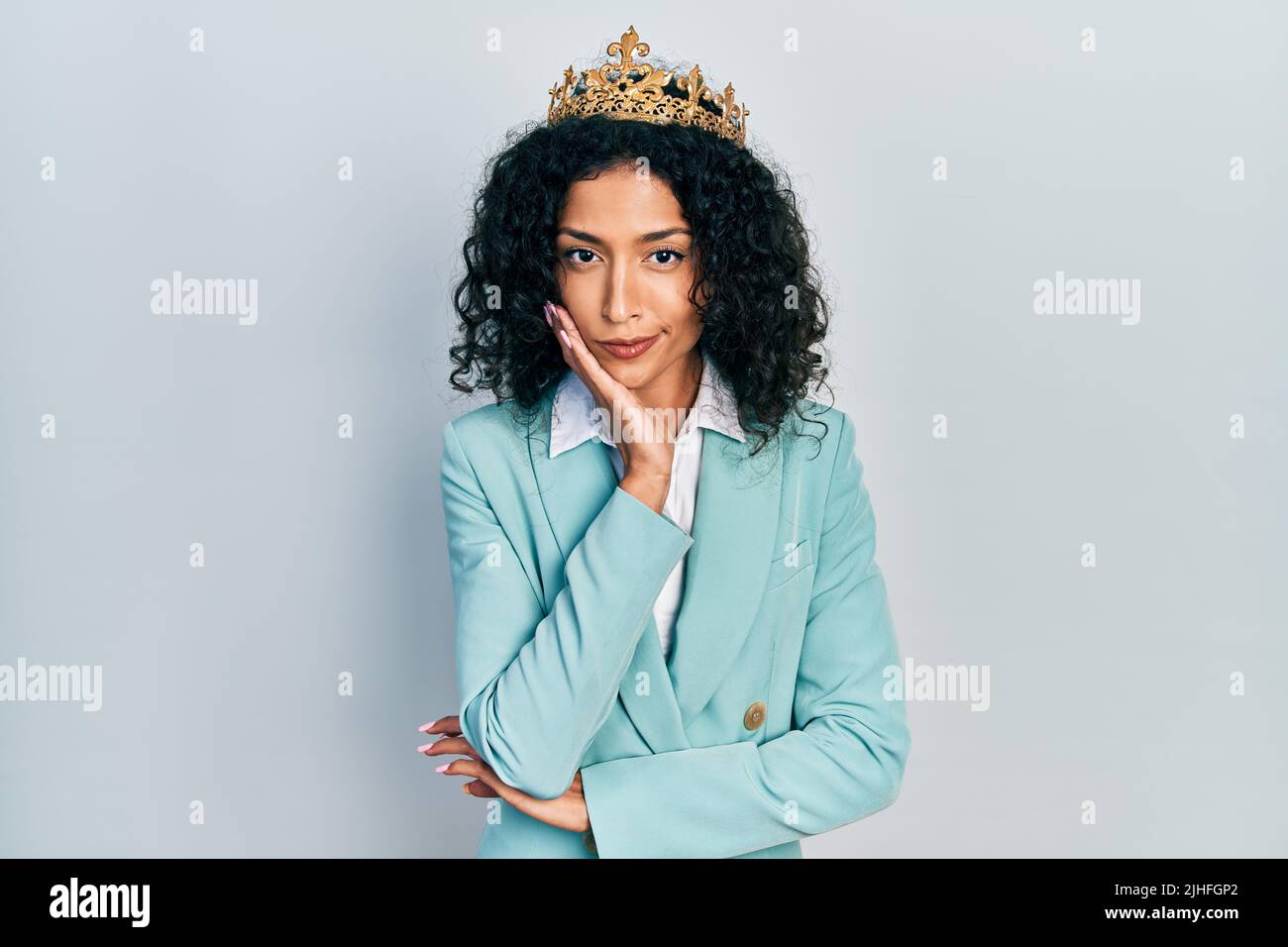 Young latin girl wearing business clothes and queen crown thinking ...