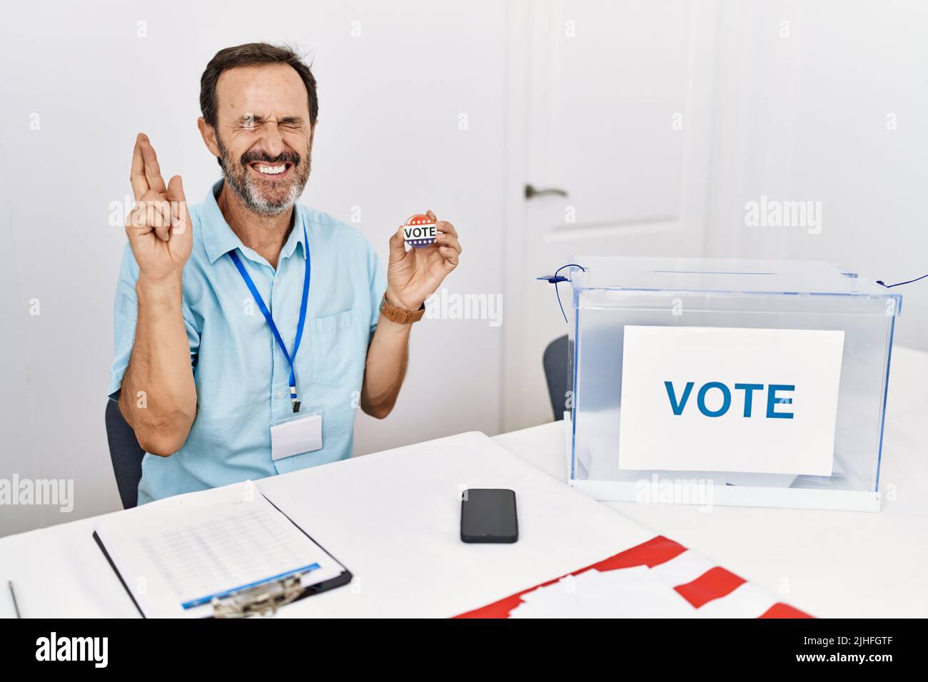 Middle age man with beard sitting by ballot holding i vote badge ...