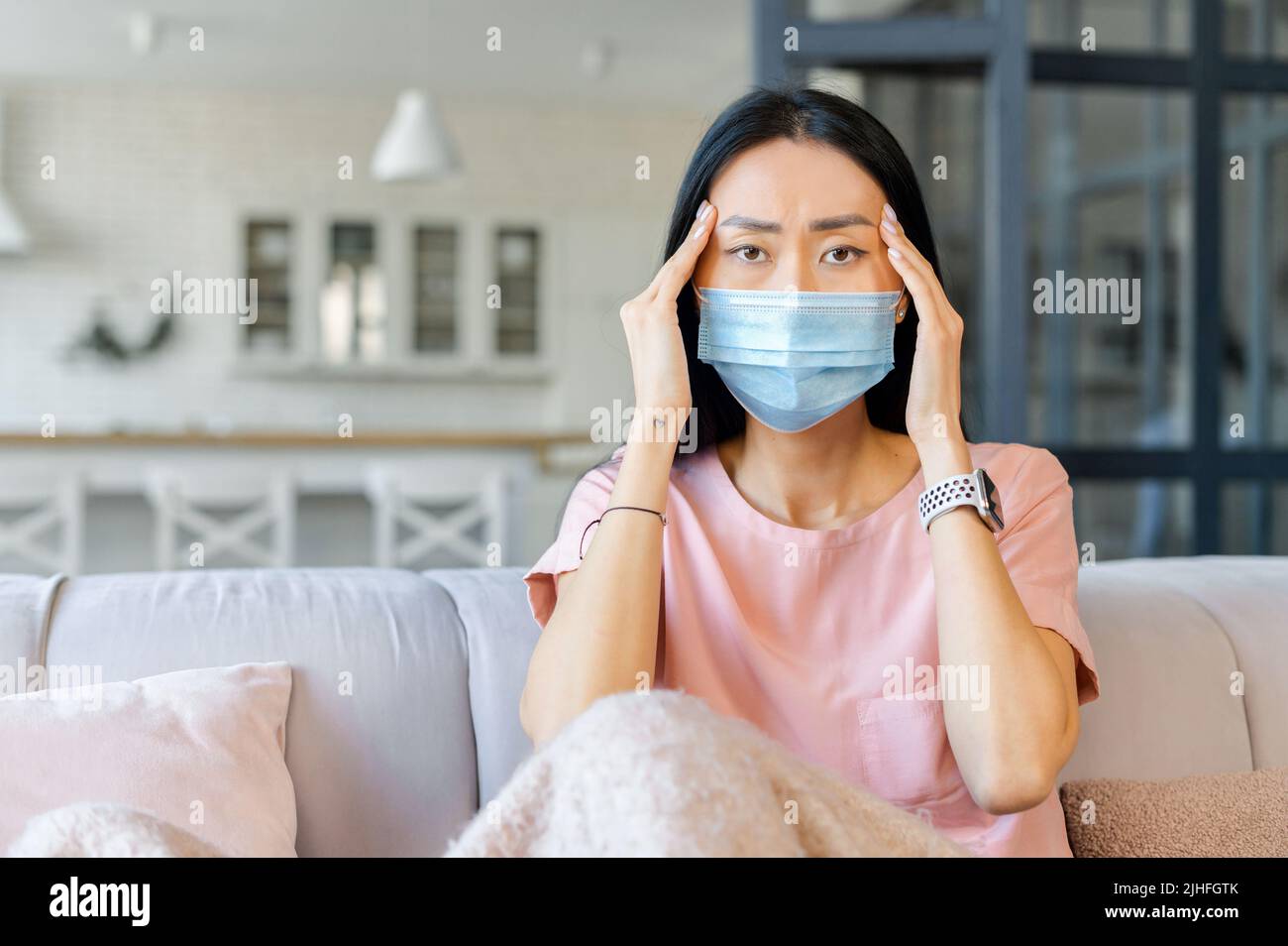 Depressed woman in protective mask sitting at home, feels sick ...