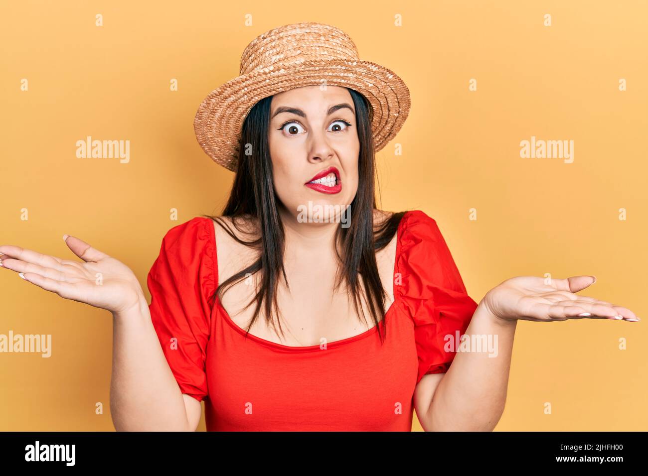 Young hispanic woman wearing summer hat clueless and confused ...