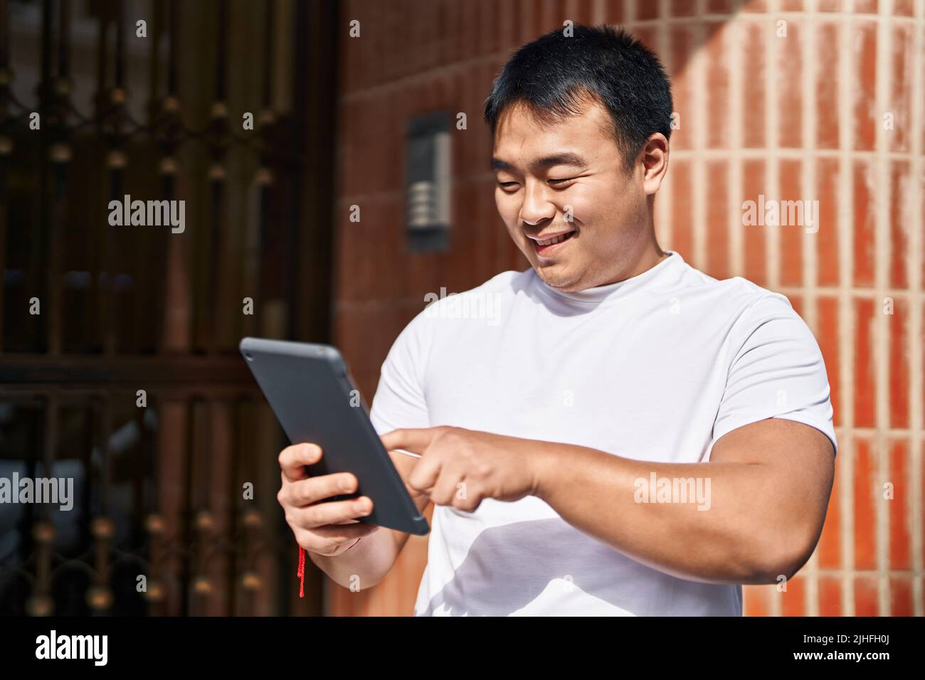 Young chinese man smiling confident using touchpad at street Stock ...