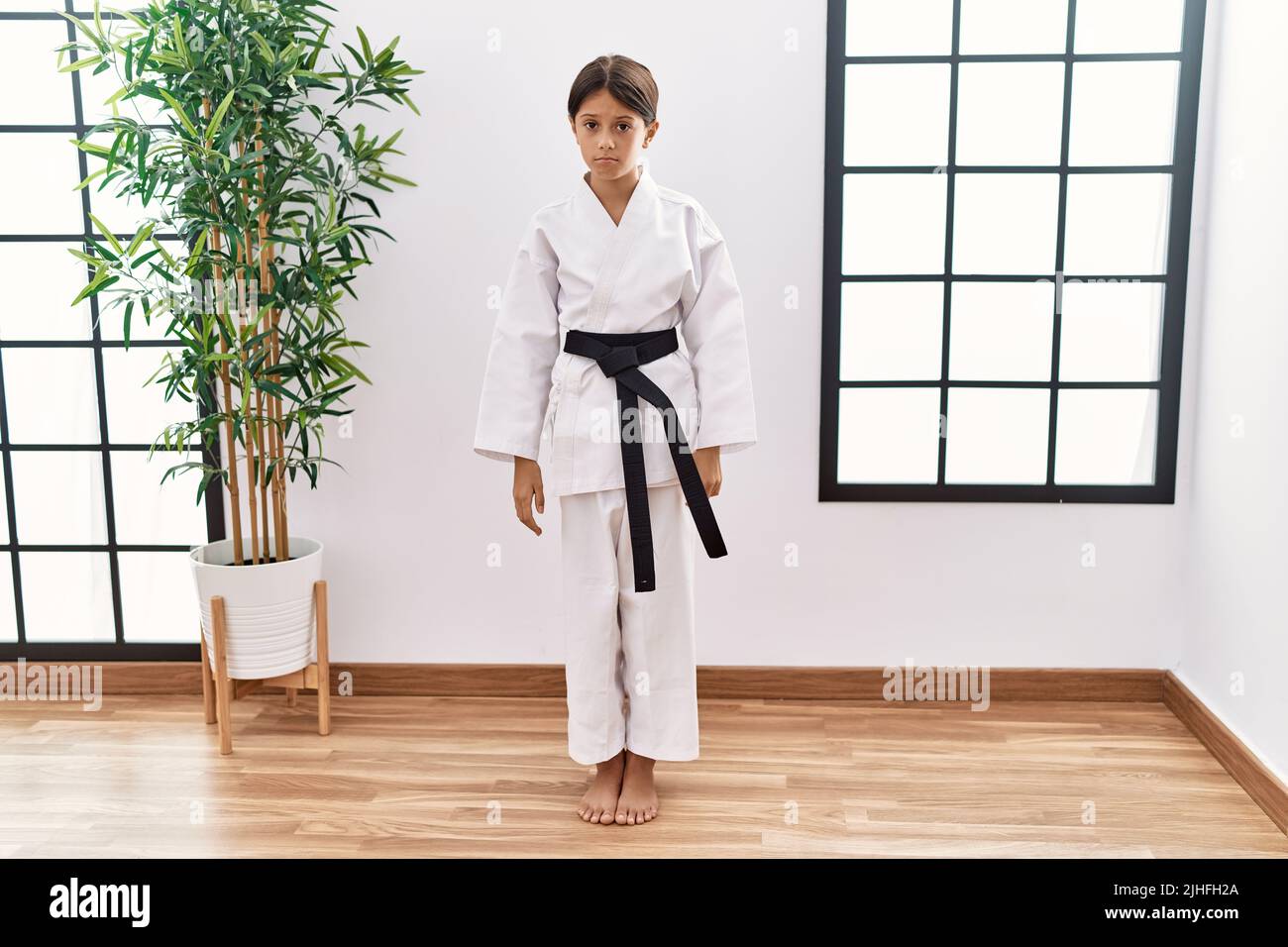 Young hispanic girl wearing karate kimono and black belt depressed and ...