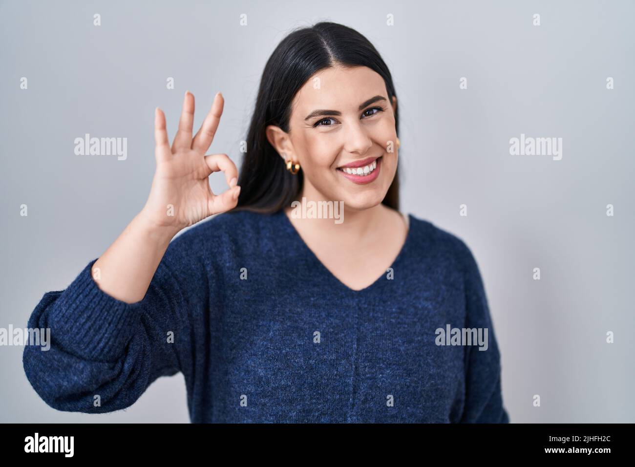 Young brunette woman standing over isolated background smiling positive ...