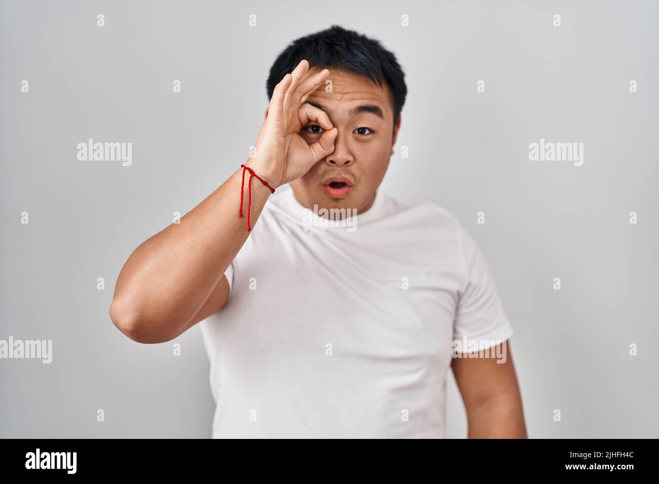 Young chinese man standing over white background doing ok gesture ...