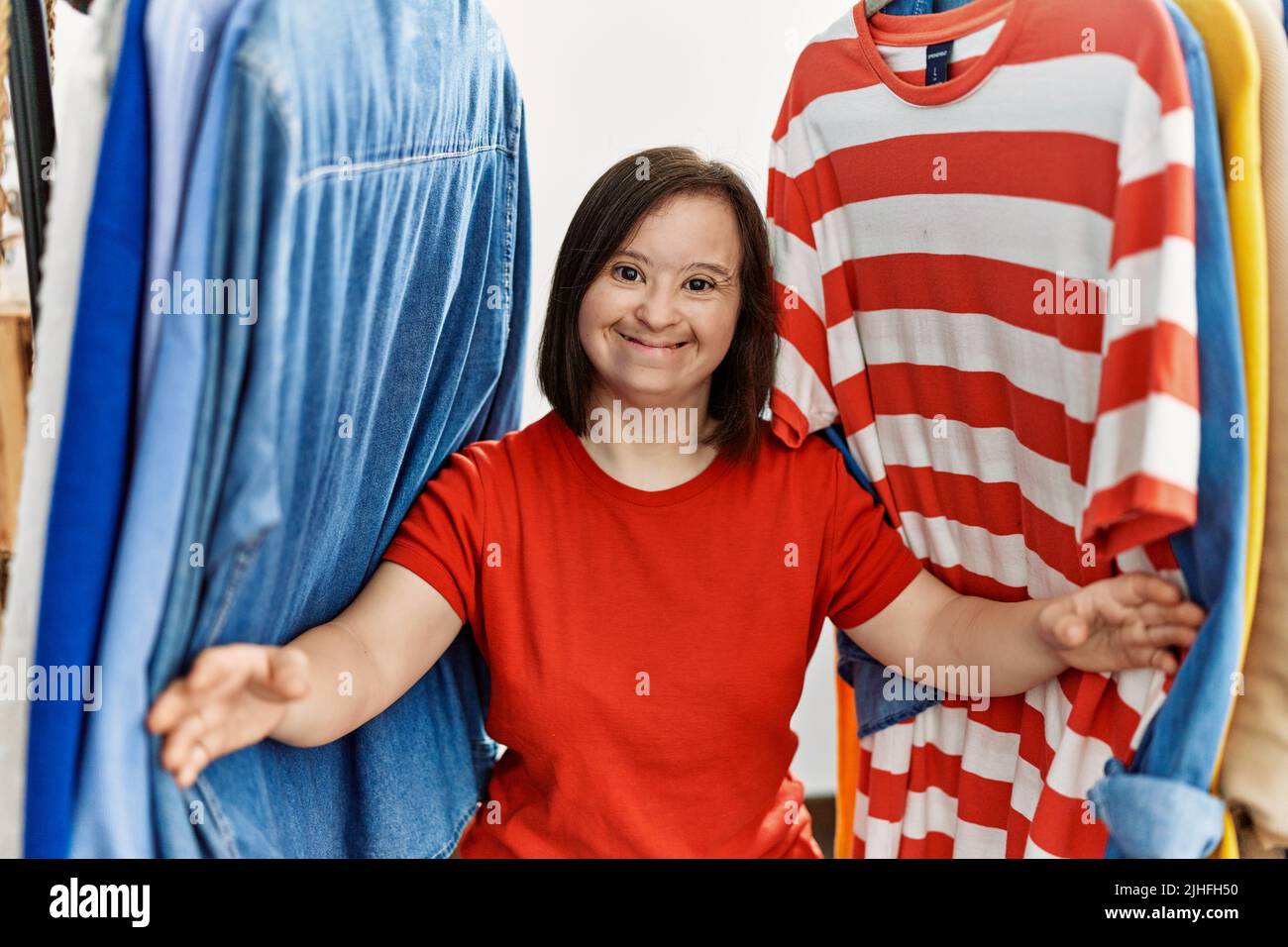 Brunette woman with down syndrome standing between hangers with ...