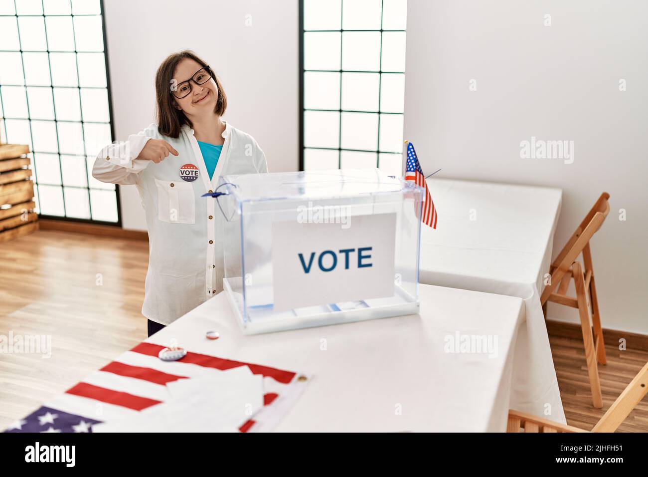 Brunette woman with down syndrome smiling showing vote badge at ...