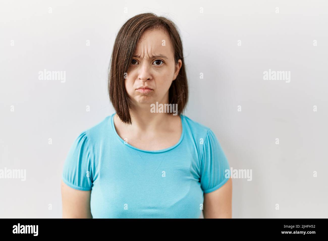 Young down syndrome woman standing over isolated background relaxed ...