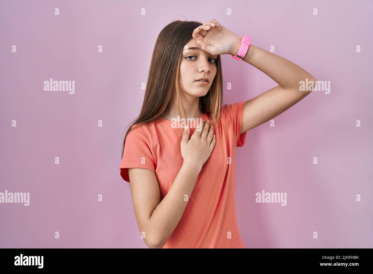 Teenager girl standing over pink background touching forehead for ...