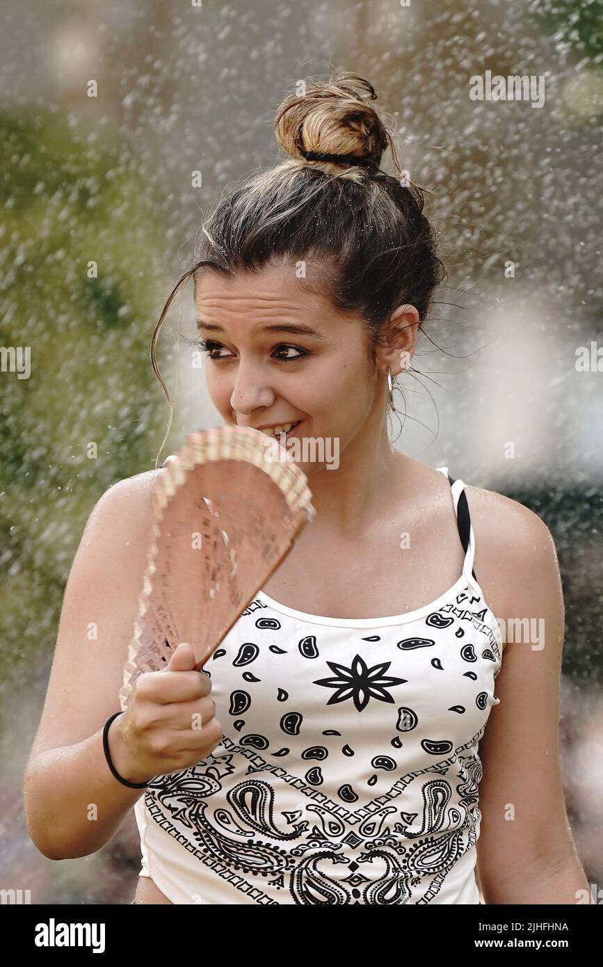 A person standing under a water sprinkler outside Queen Elizabeth II Centre in central London ...