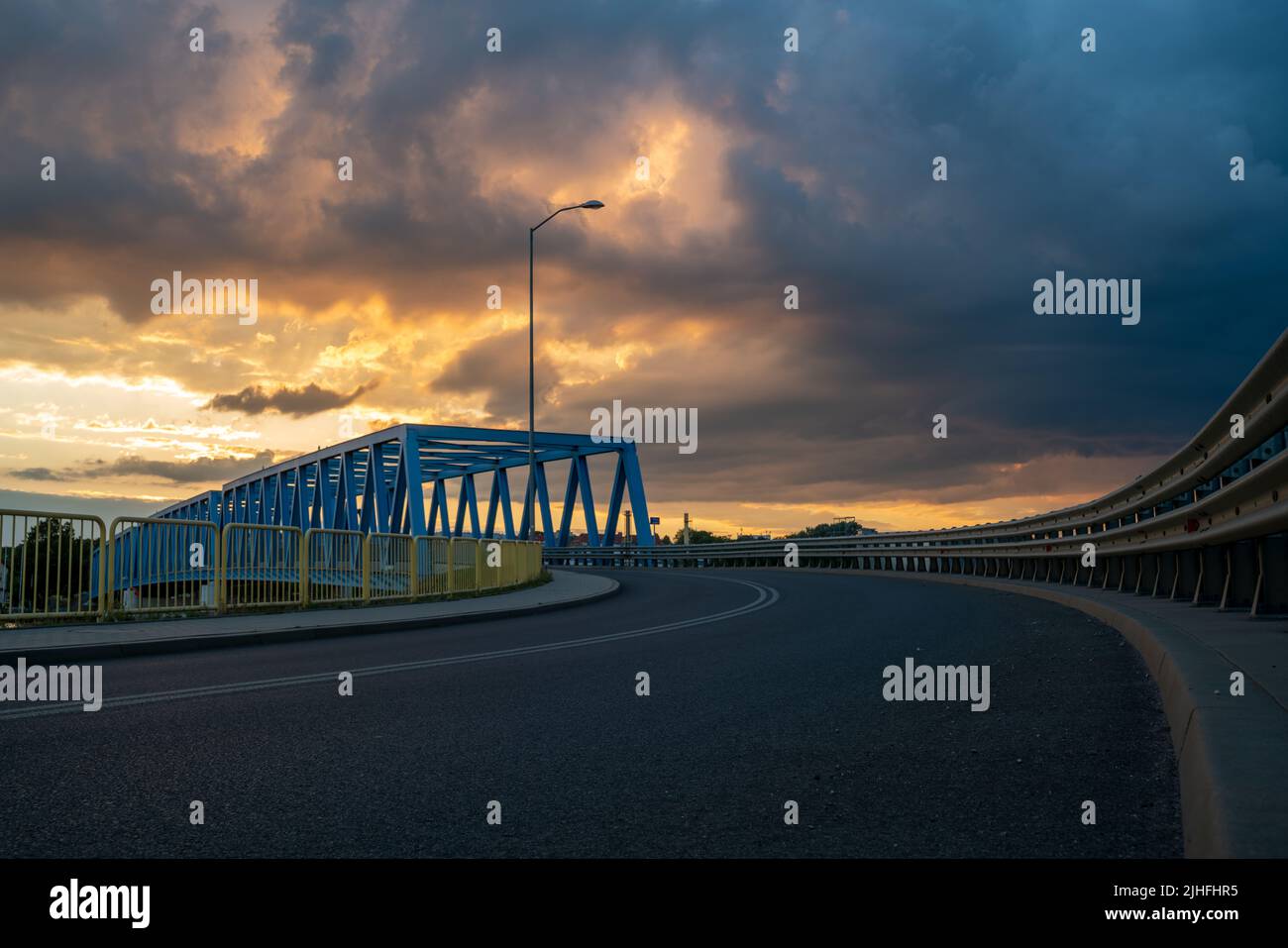 Asphalt road and truss bridge during an evening storm Stock Photo - Alamy