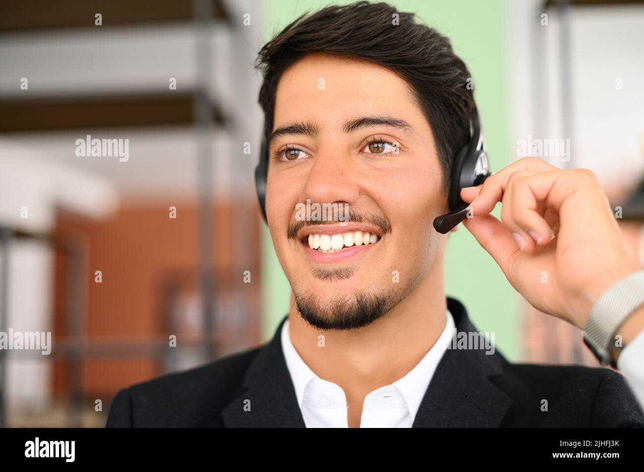 Smiling young latin male office employee wearing using headset and ...