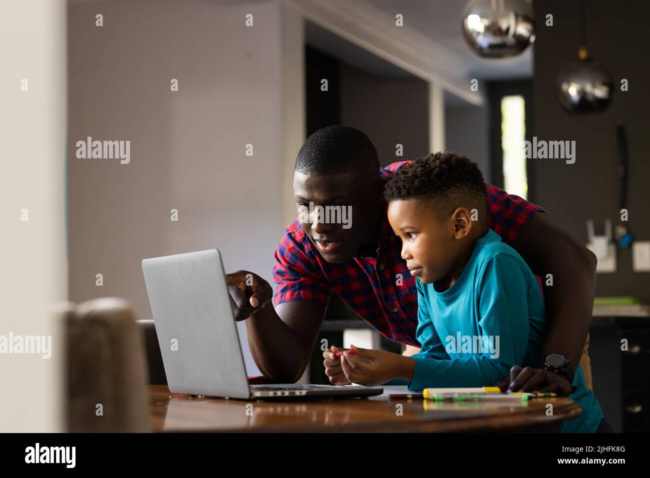 Image of smiling african american boy with father using laptop Stock ...