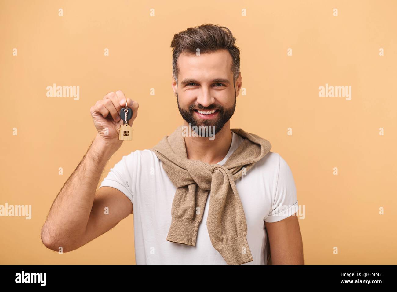 Happy young guy showing keys standing isolated on beige, happy man with ...