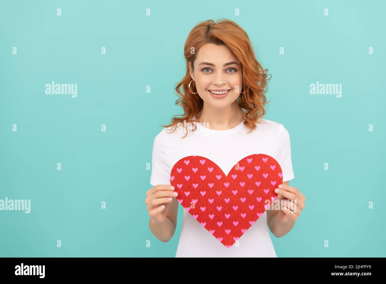 cheerful redhead woman hold red heart on blue background Stock Photo ...