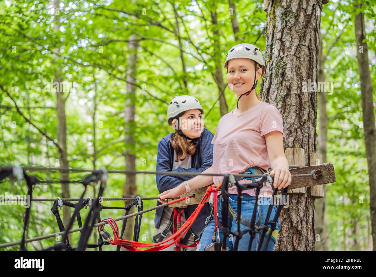 Two women girls female gliding climbing in extreme road trolley zipline ...