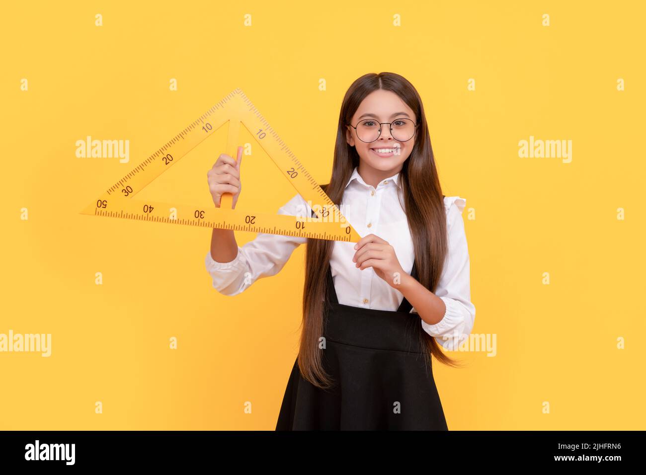 cheerful child in school uniform and glasses hold mathematics triangle ...