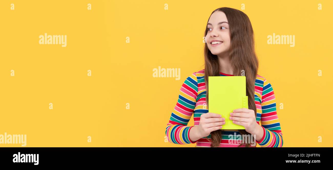 Happy girl child smile holding book yellow background. Portrait of ...