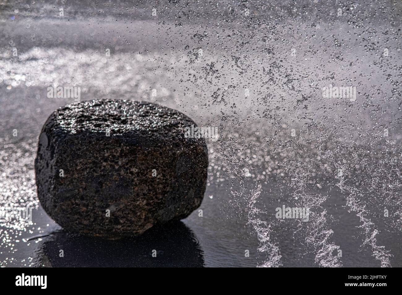 A close-up shot of a big rock surrounded by water droplets Stock Photo ...