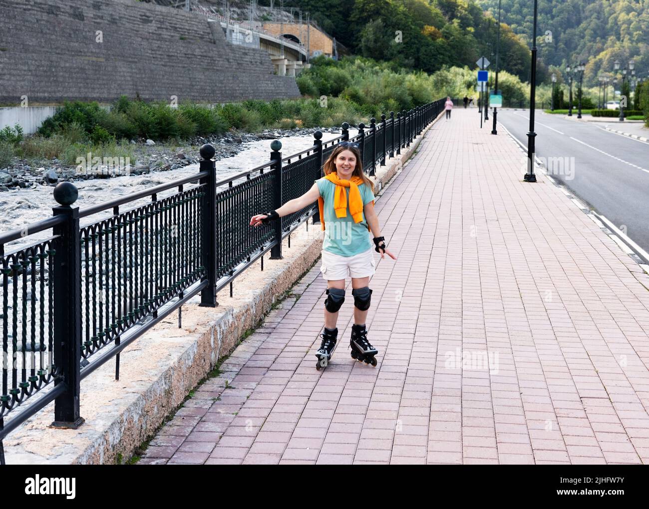 happy beautiful young woman in protective equipment riding on roller ...