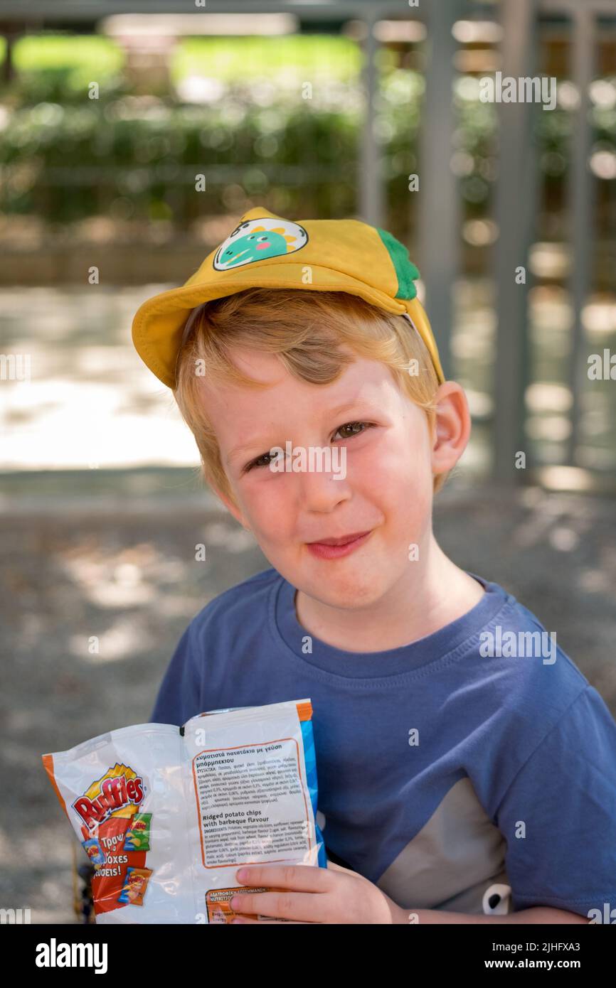 Cute little boy eating chips in the park Stock Photo - Alamy