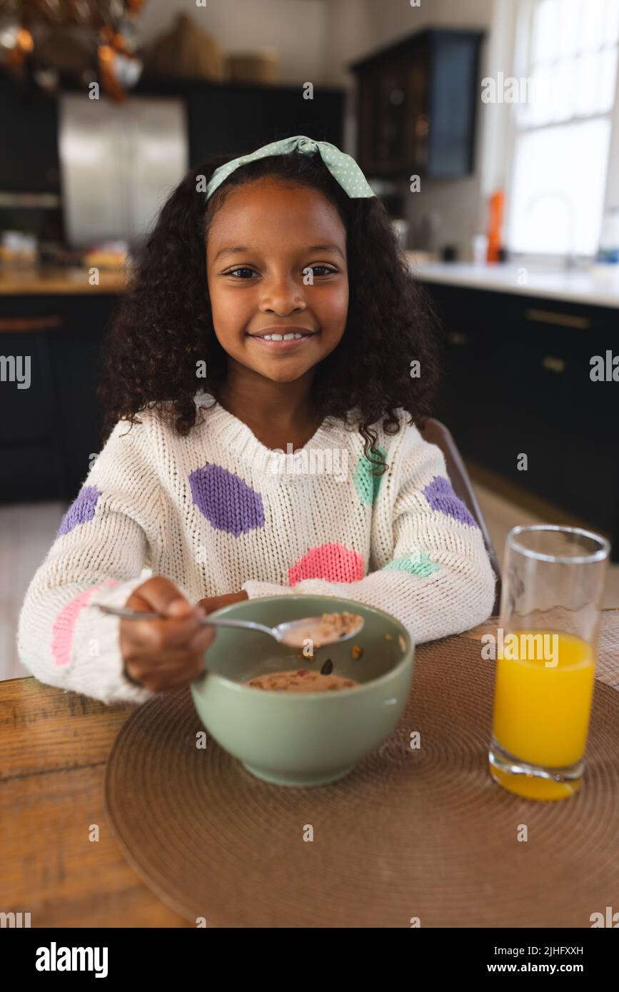 Vertical image of happy african american girl eating breakfast Stock Photo - Alamy