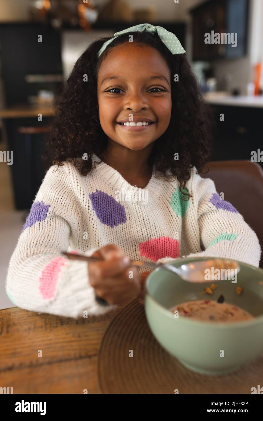 Vertical image of happy african american girl eating breakfast Stock ...