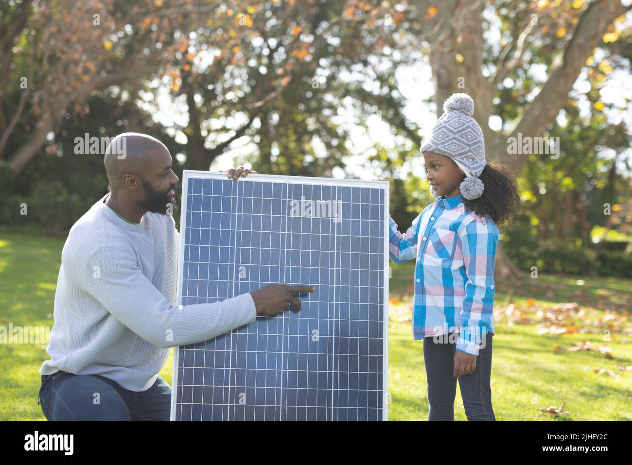 Image of happy african american father showing solar panels to daughter ...