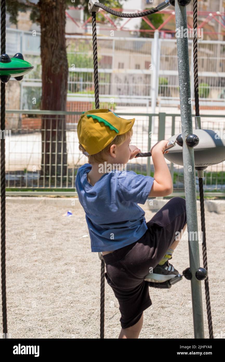 Little boy climbing ropes in the playground Stock Photo - Alamy