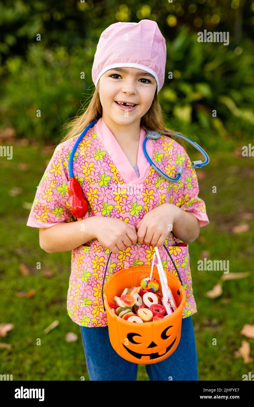 Vertical image of happy caucasian girl in doctor costume in autumn ...