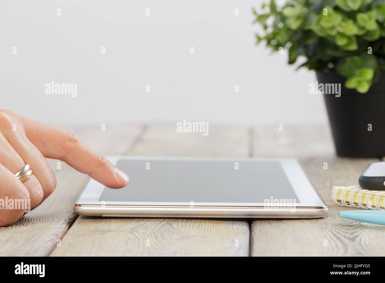 hands of a man holding tablet device over a wooden workspace table ...