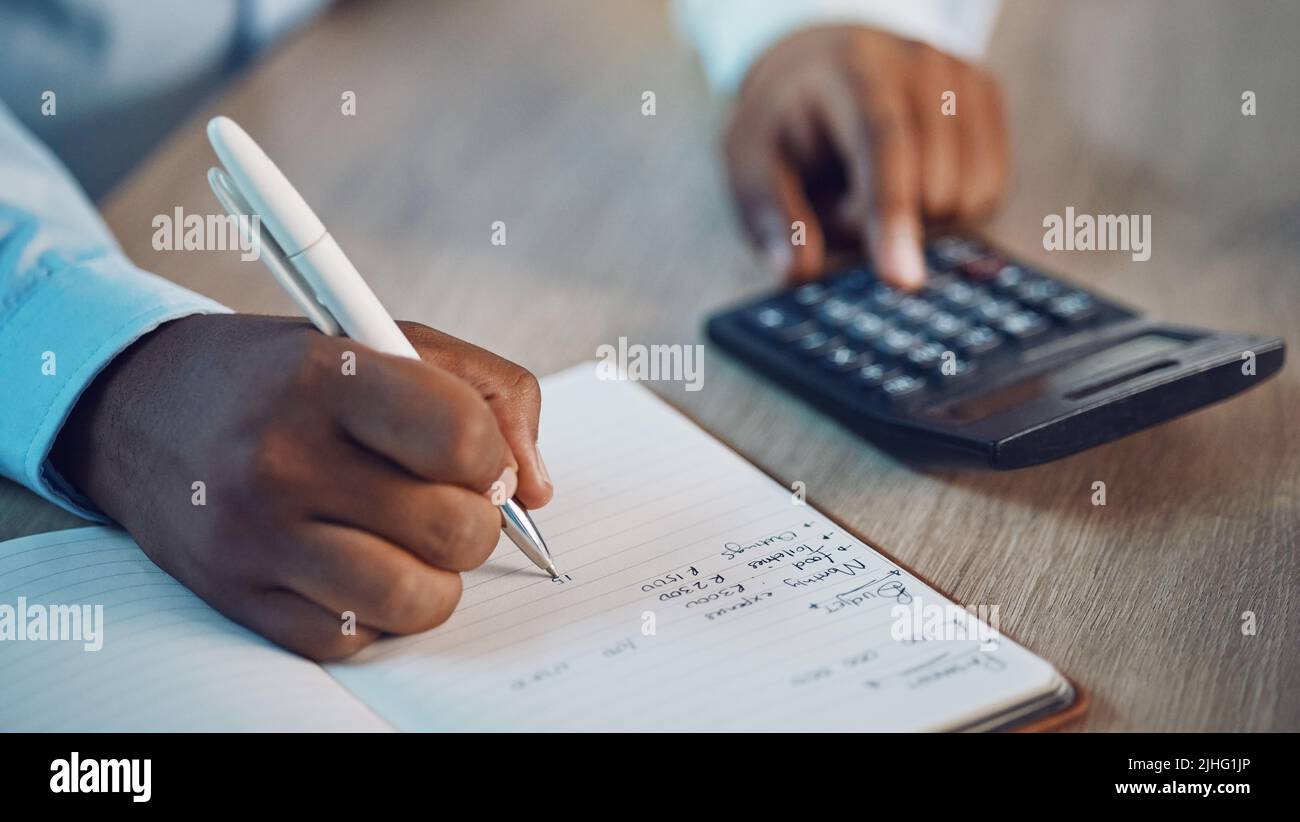 Closeup hands of african man writing in his diary while using a ...