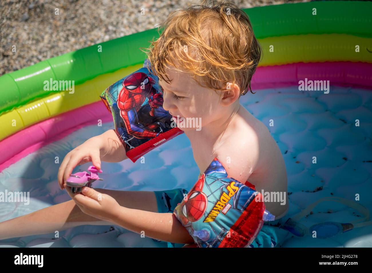 Cute little boy playing in his inflatable pool wearing inflatable ...