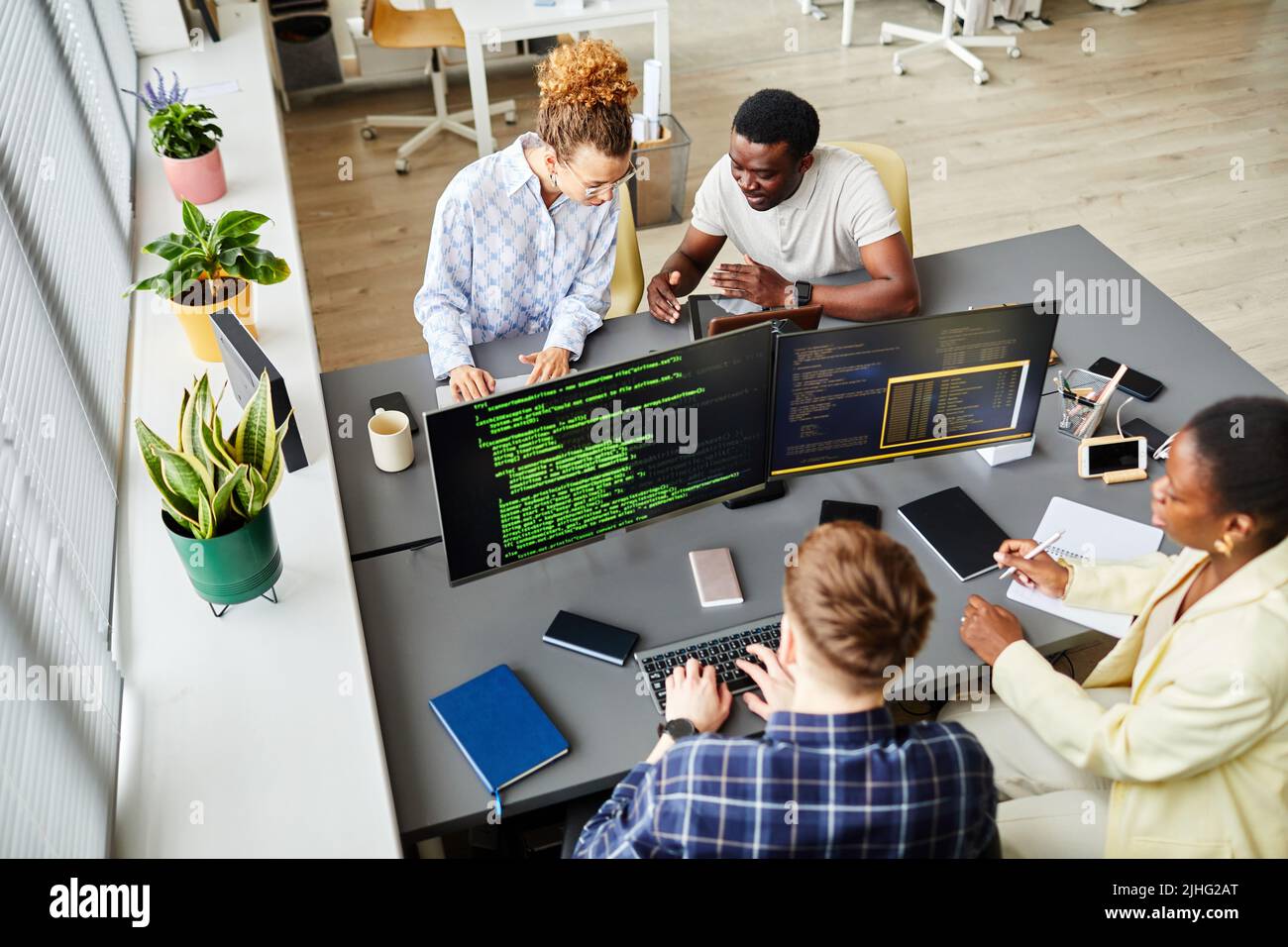 High angle view of programmers sitting at table with computer monitors ...