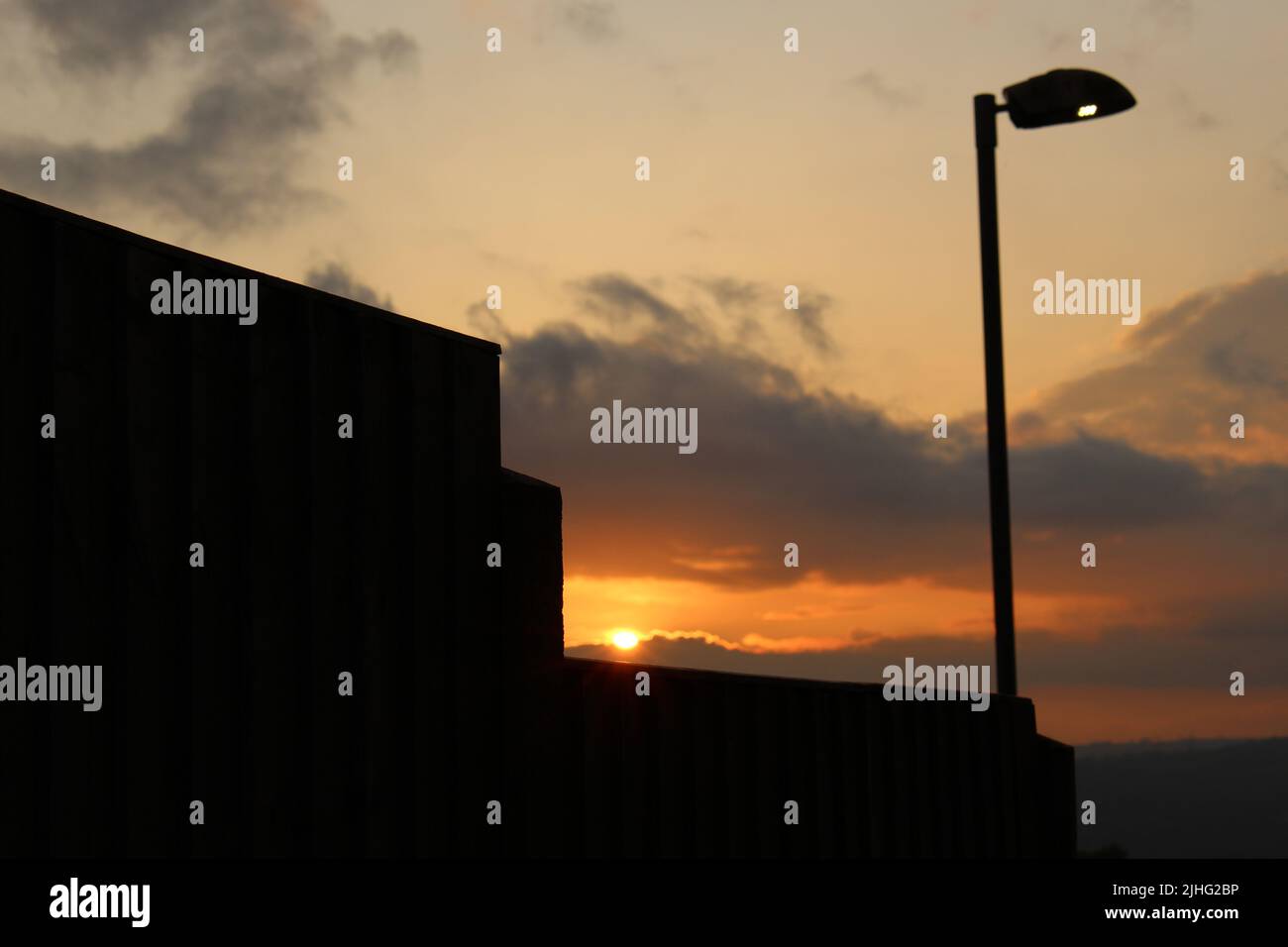 Sun setting over concrete wall in urban landscape with lamp overlooking ...