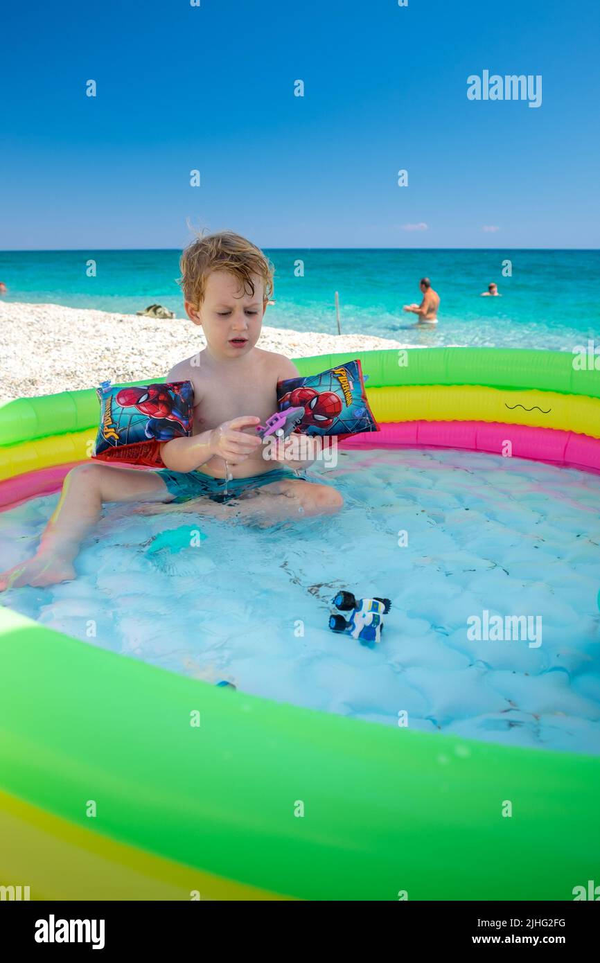 Cute little boy playing in his inflatable pool wearing inflatable ...