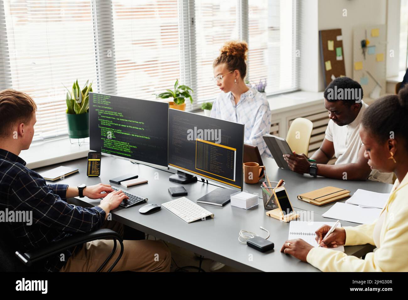 Multiethnic group of programmers working on computer and making plan in ...