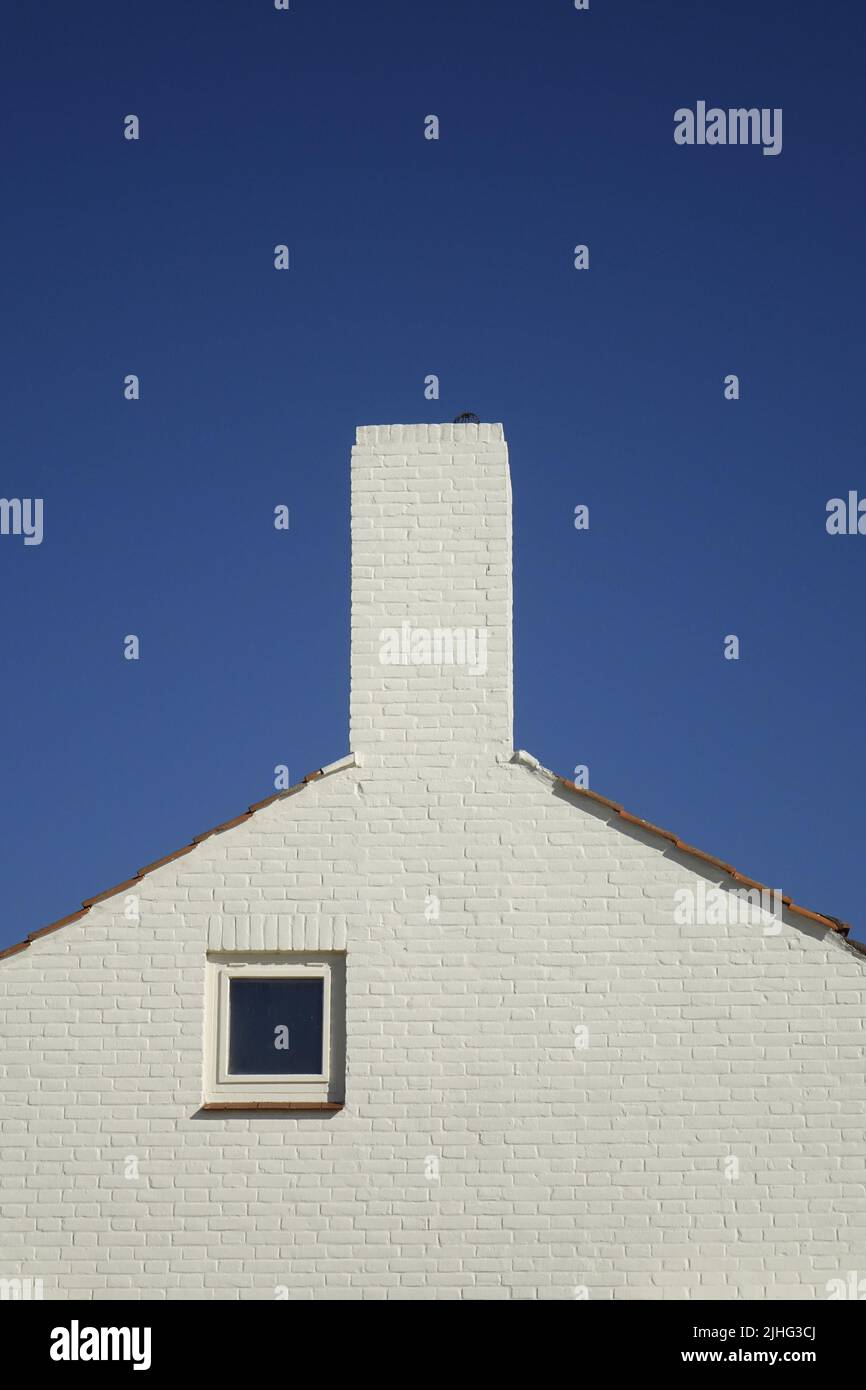 A vertical shot of a white brick building against the blue sky ...