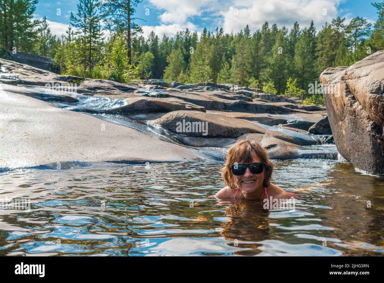 Woman swimming at Storforsen nature reserve, enjoying in summer time ...