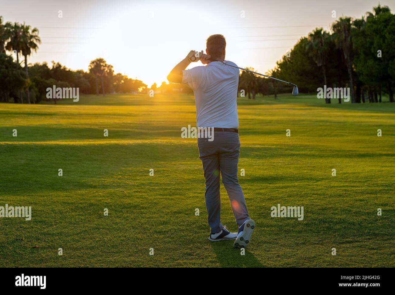 Good strike, golfer swinging his driver and looking away while standing ...