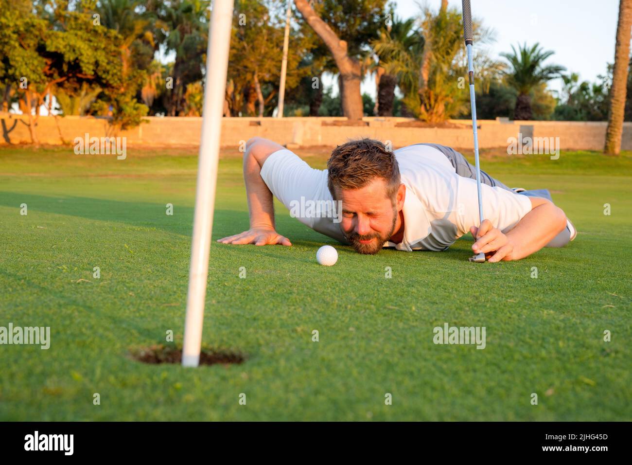 Pro golf player aiming shot with club on course. Male golfer on putting ...
