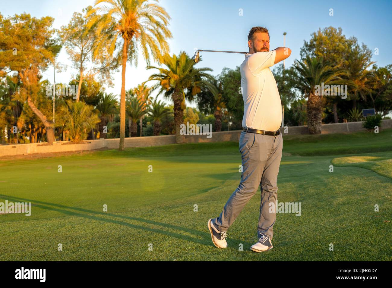 Good strike, golfer swinging his driver and looking away while standing ...