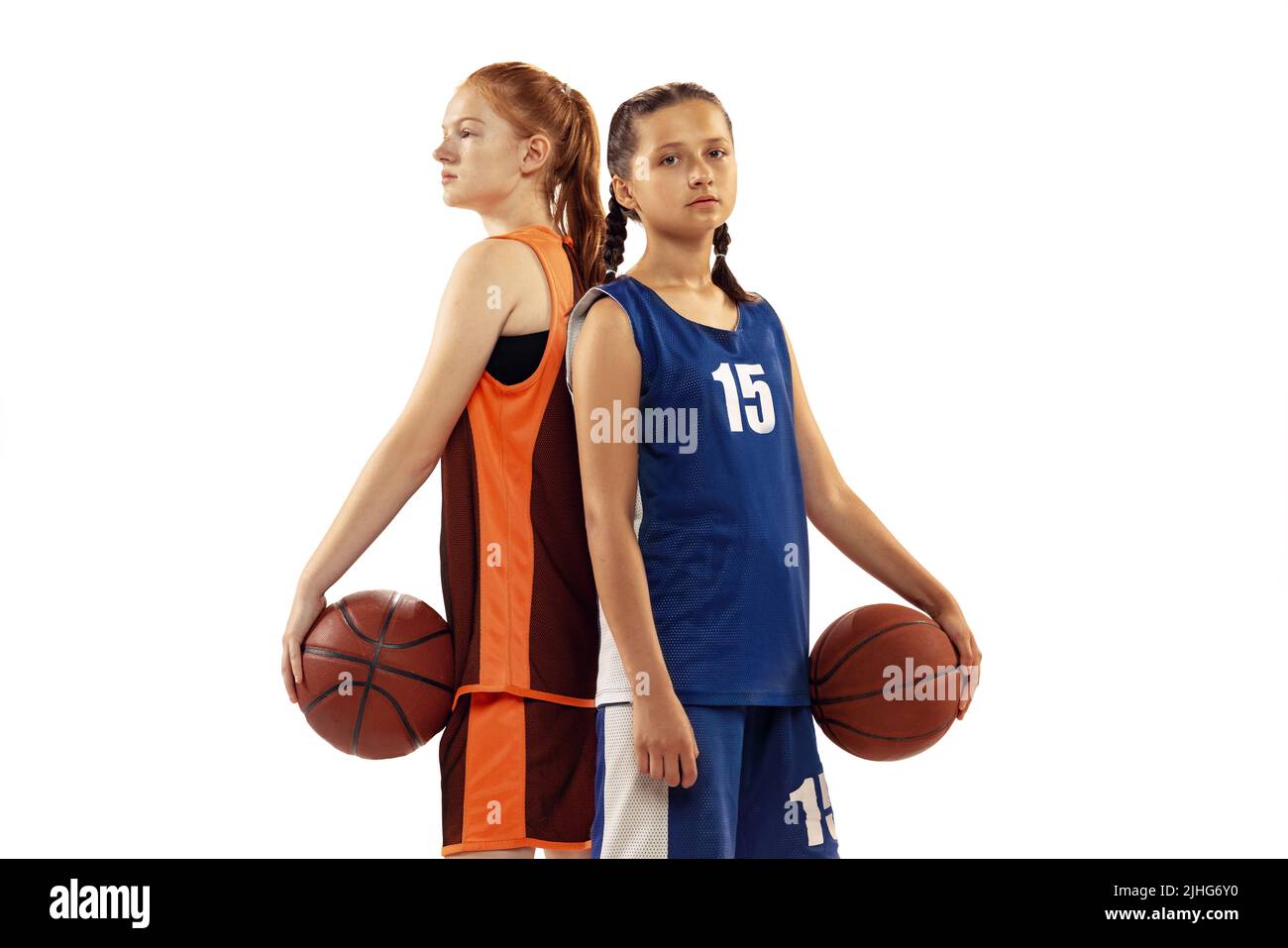 Portrait of two young girls, basketball players posing with basketball ...