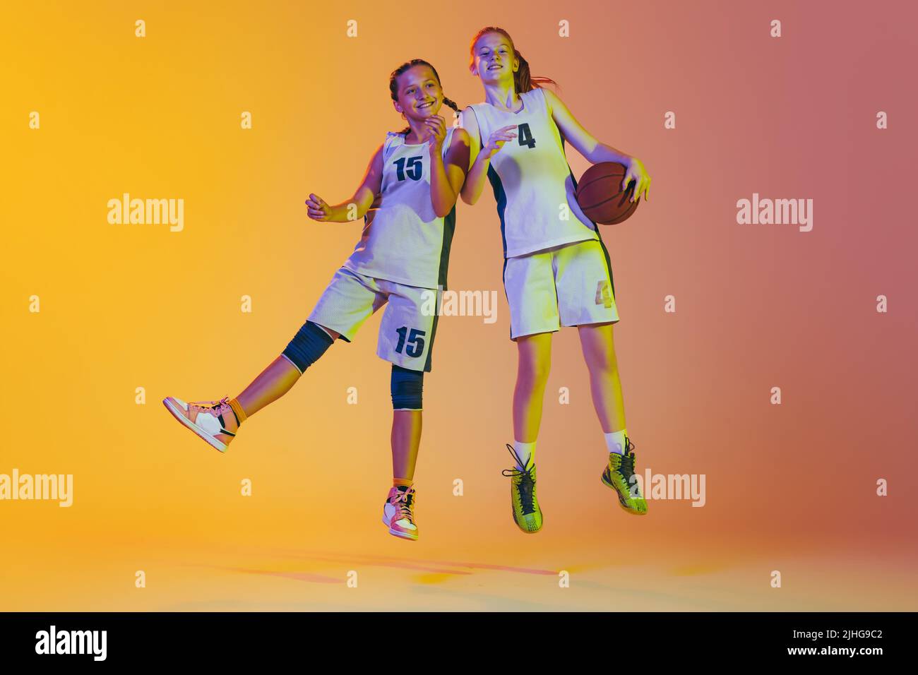 Happy girls, basketball players in action isolated on neoned background ...