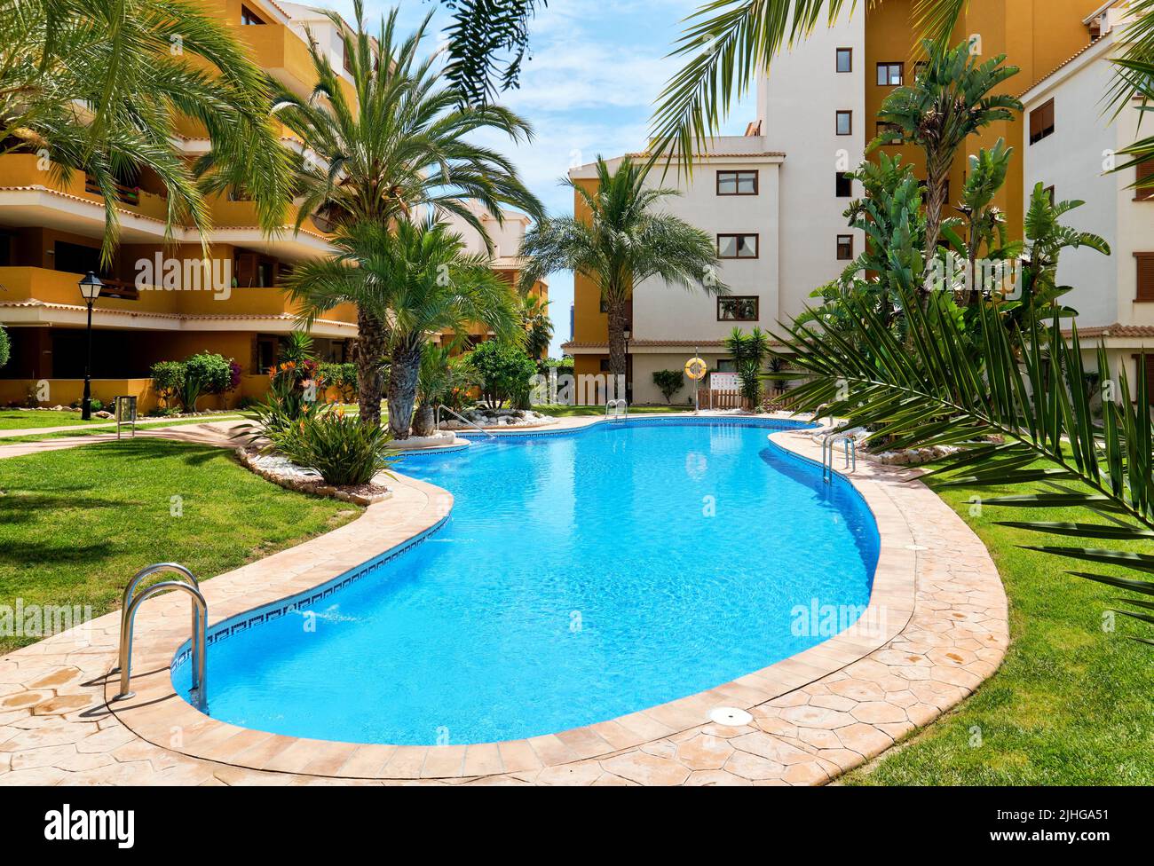 A swimming pool area between high-rise buildings in Punta Prima ...