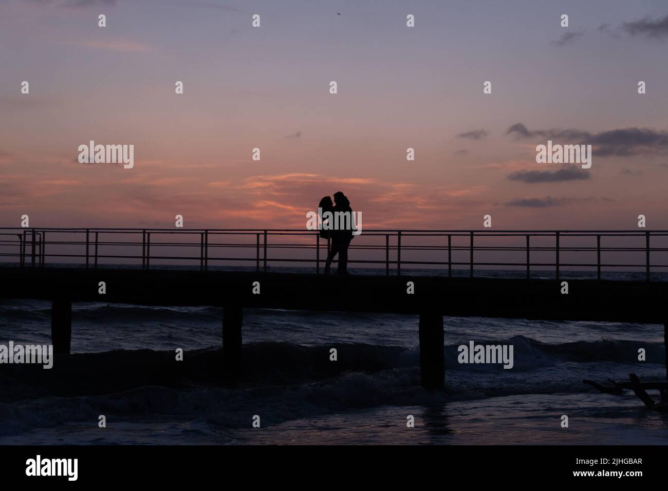 couple kissing at the sunset on the pier Stock Photo - Alamy