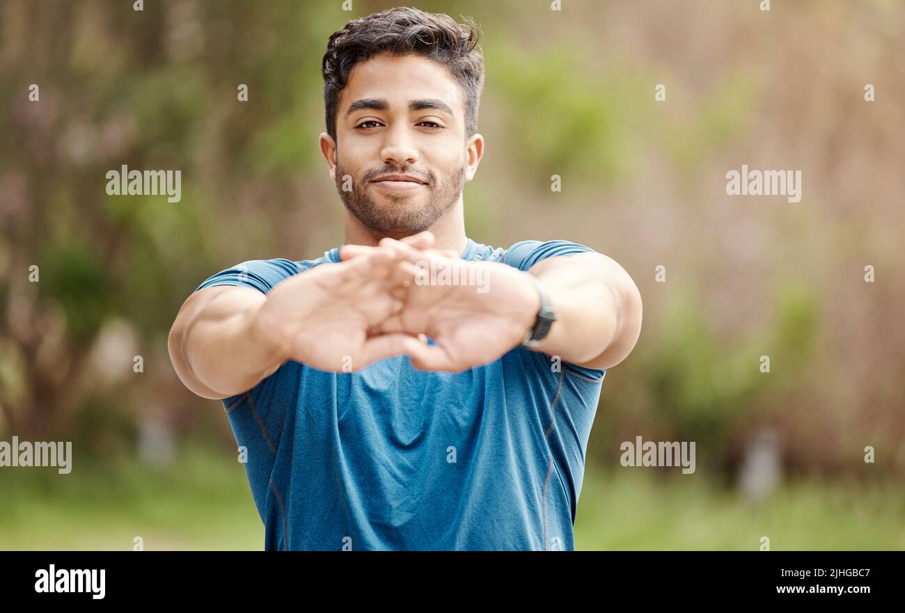 Portrait of one fit young indian man stretching arms for warmup to ...