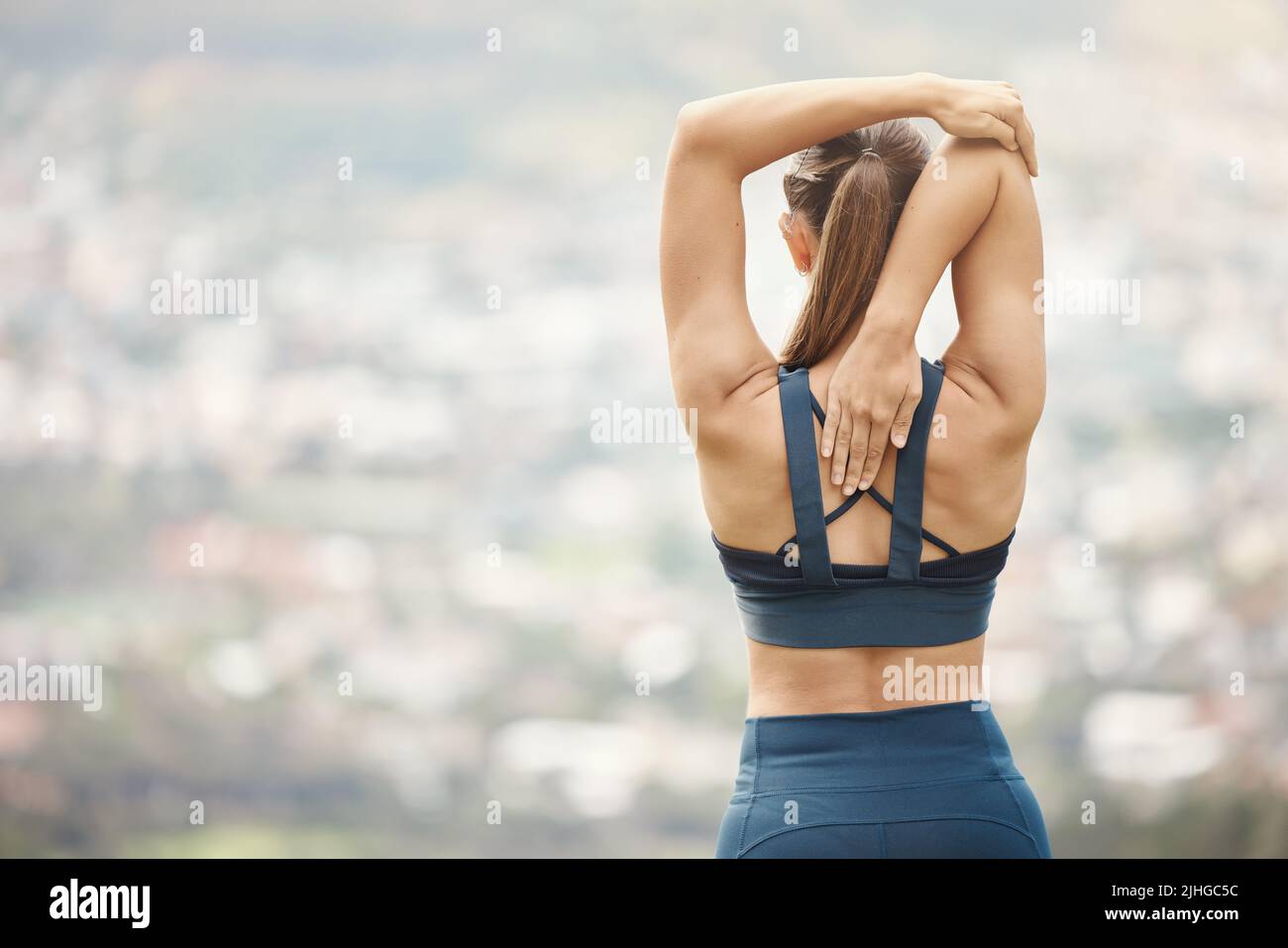 One active mixed race woman from the back stretching arms and triceps ...