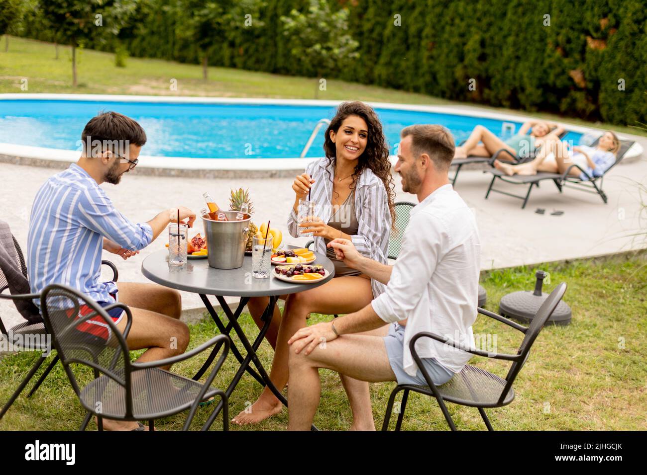 Group of happy young people cheering with drinks and eating fruits by ...