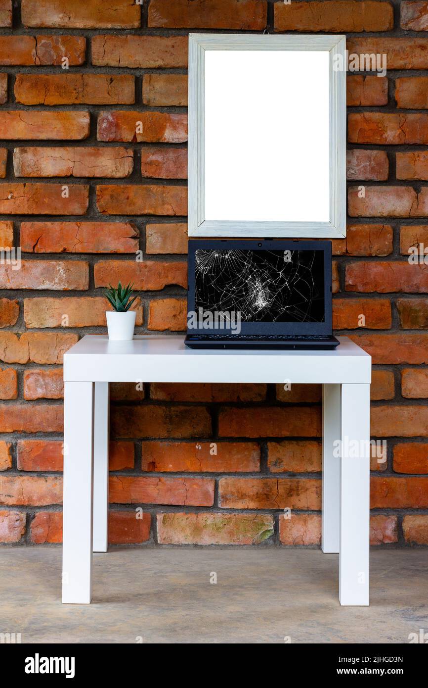 a black laptop with a broken screen on a white table against an old ...