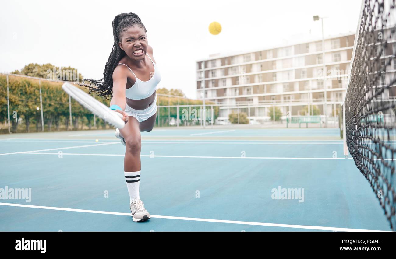 Strong tennis player hitting a ball during a match. Young girl making a ...